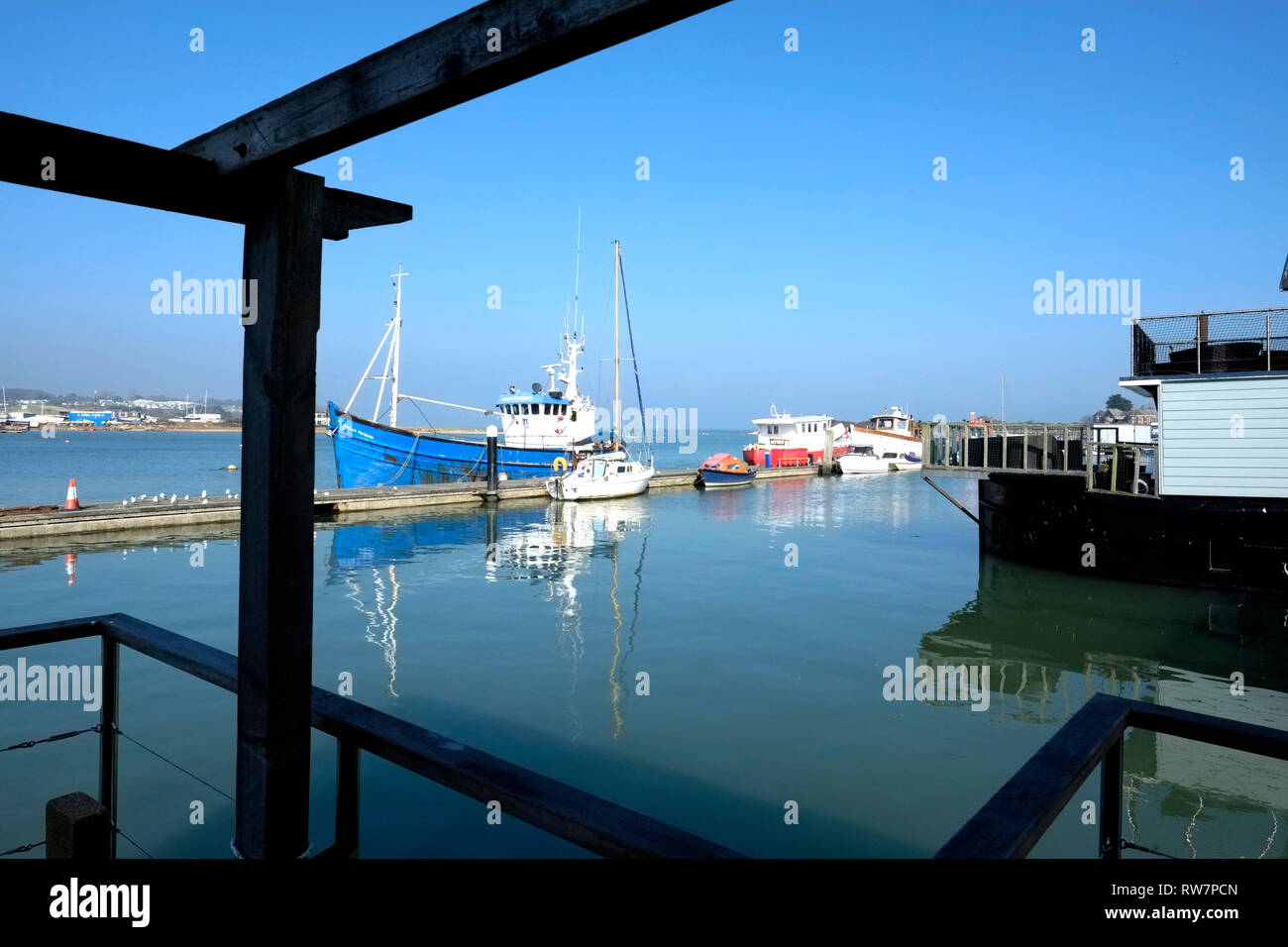 A fishing trawler docked at a pontoon on the calm waters of Bembridge ...