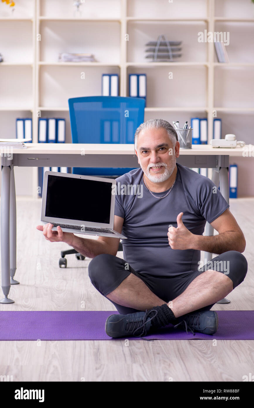 White bearded old man employee doing exercises in the office Stock ...