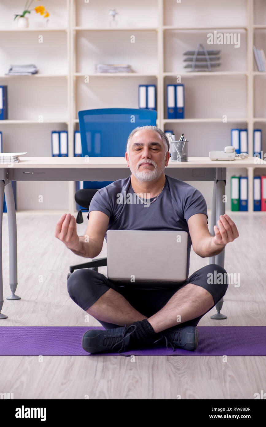 White bearded old man employee doing exercises in the office Stock ...