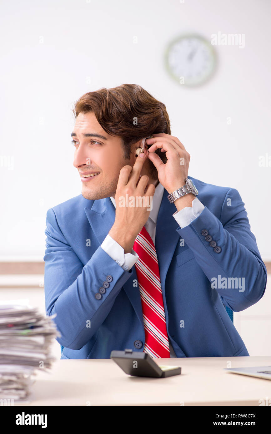 Deaf employee using hearing aid in office Stock Photo - Alamy