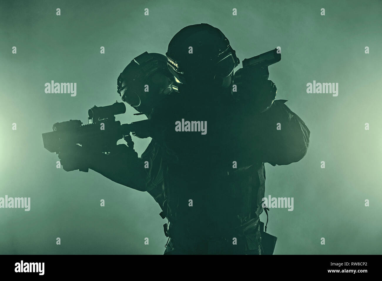 Studio shot of SWAT police special forces aiming weapons. Green smoke ...