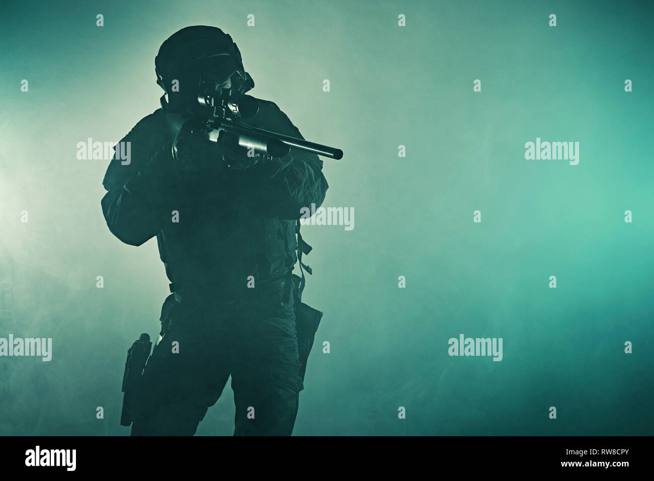 Studio shot of SWAT police operator with sniper rifle. Fire smoke ...