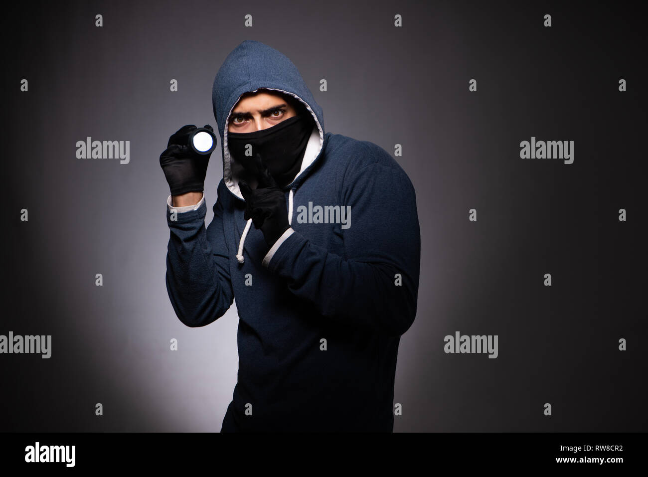 Young gangster in hood on grey background Stock Photo - Alamy