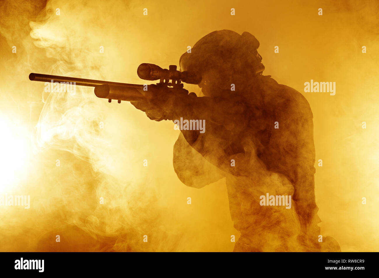 Studio shot of SWAT police operator with sniper rifle. Fire smoke ...
