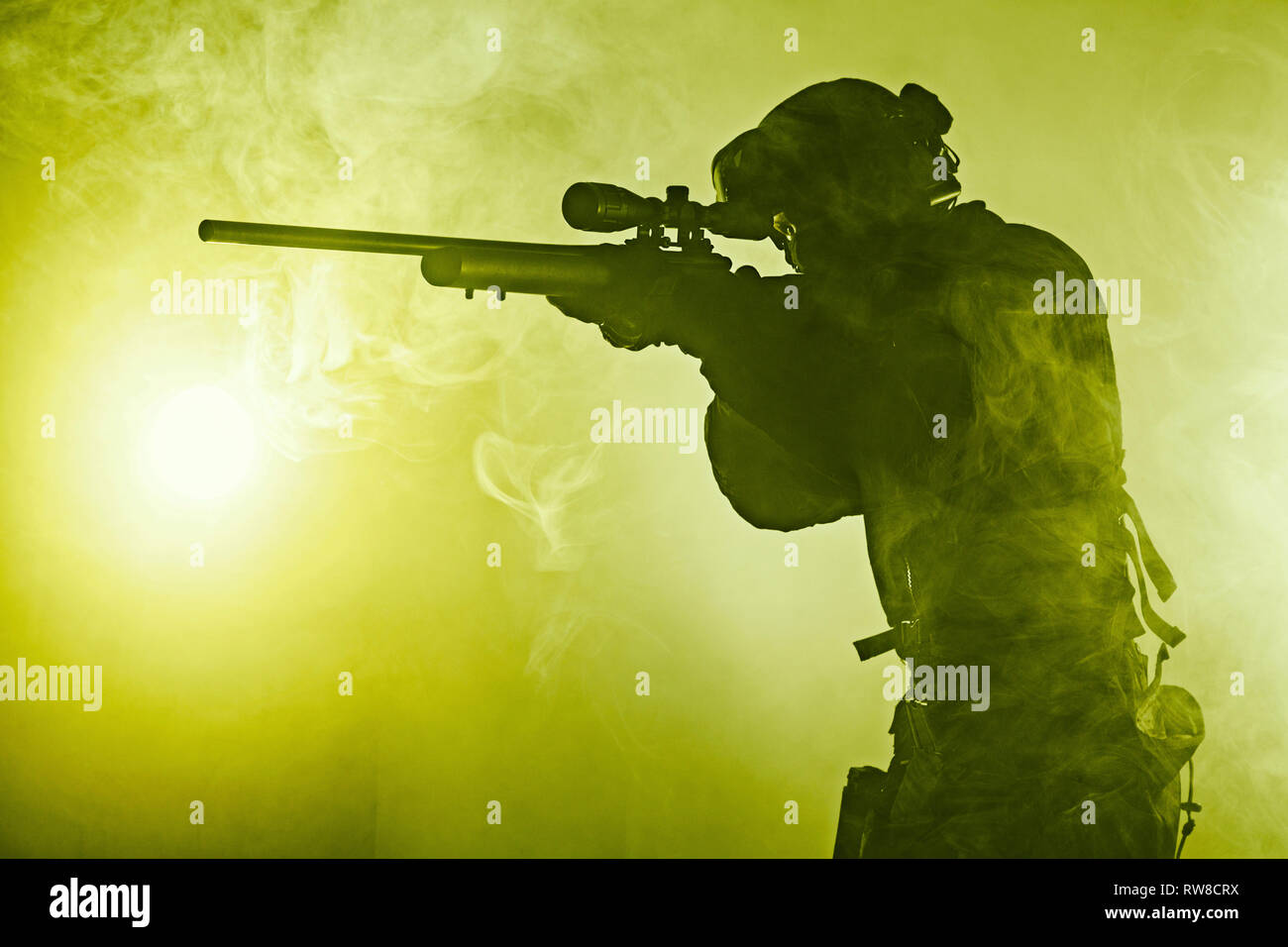 Studio shot of SWAT police operator with sniper rifle. Fire smoke ...