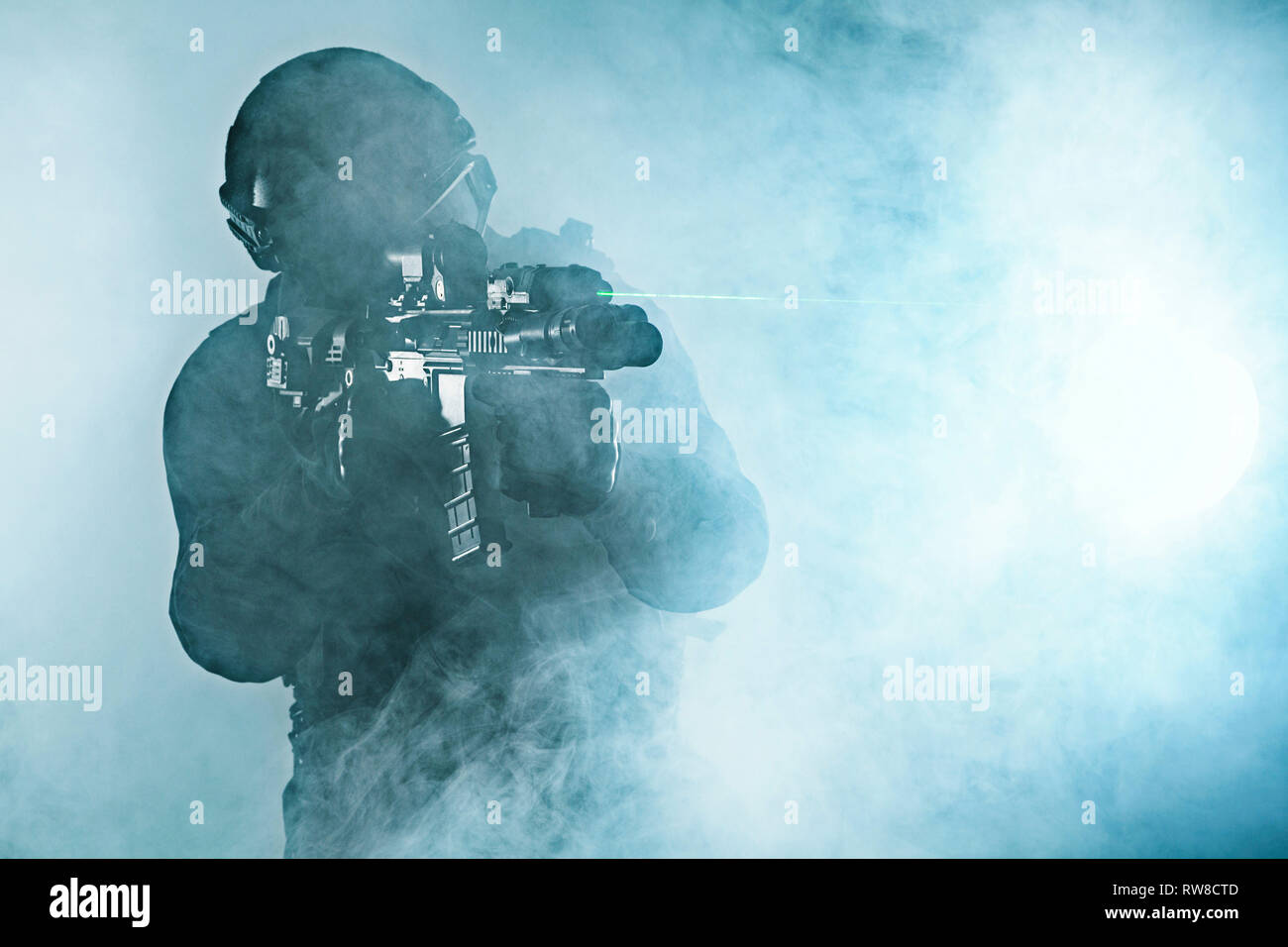 Studio shot of SWAT police operator with assault rifle. Fire smoke ...