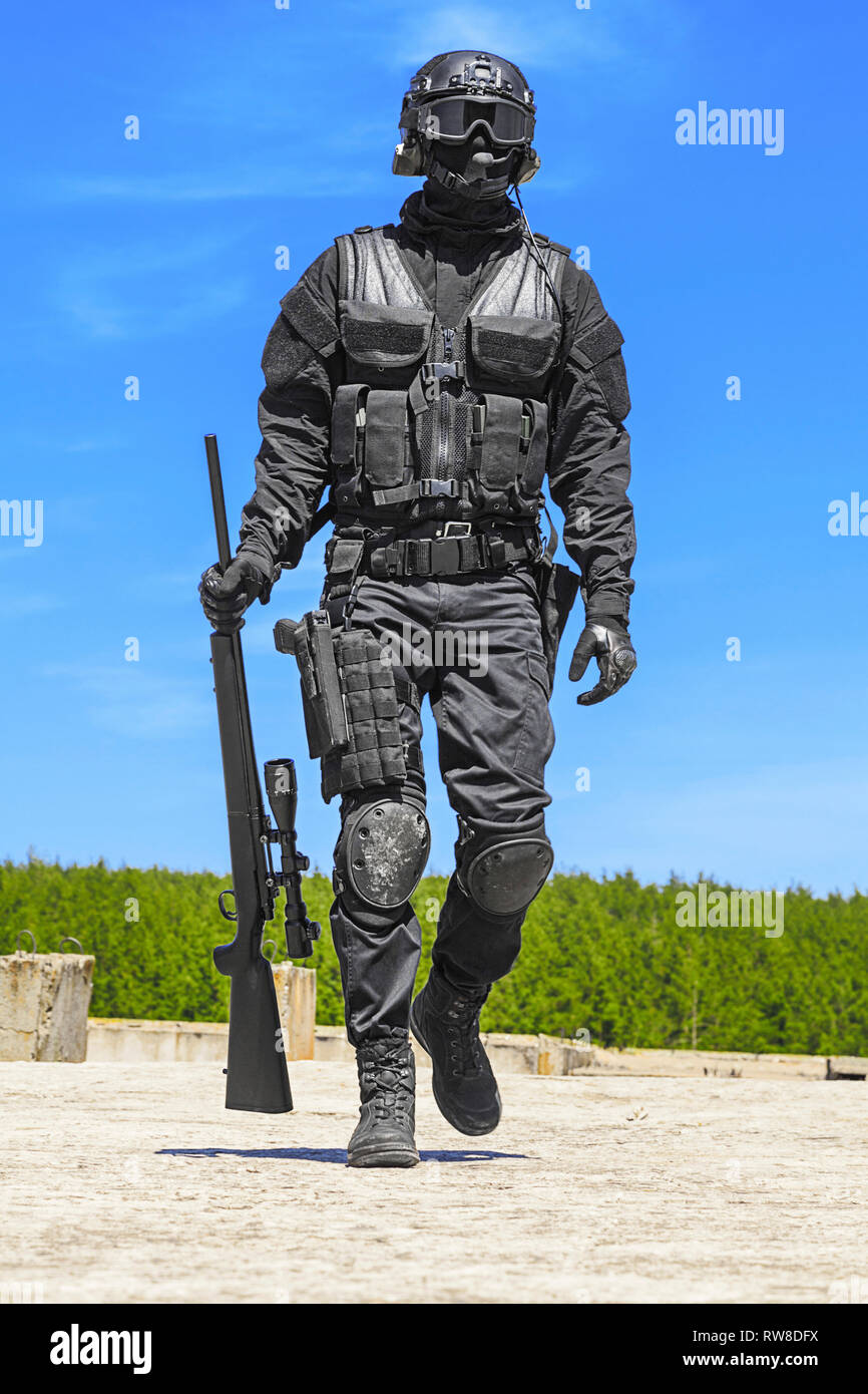 SWAT police operator with sniper rifle in black uniform, walking ...