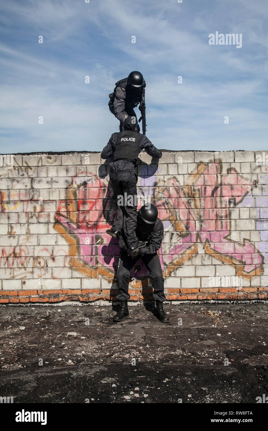 Spec ops police subdivision SWAT in action climbing over a wall Stock ...