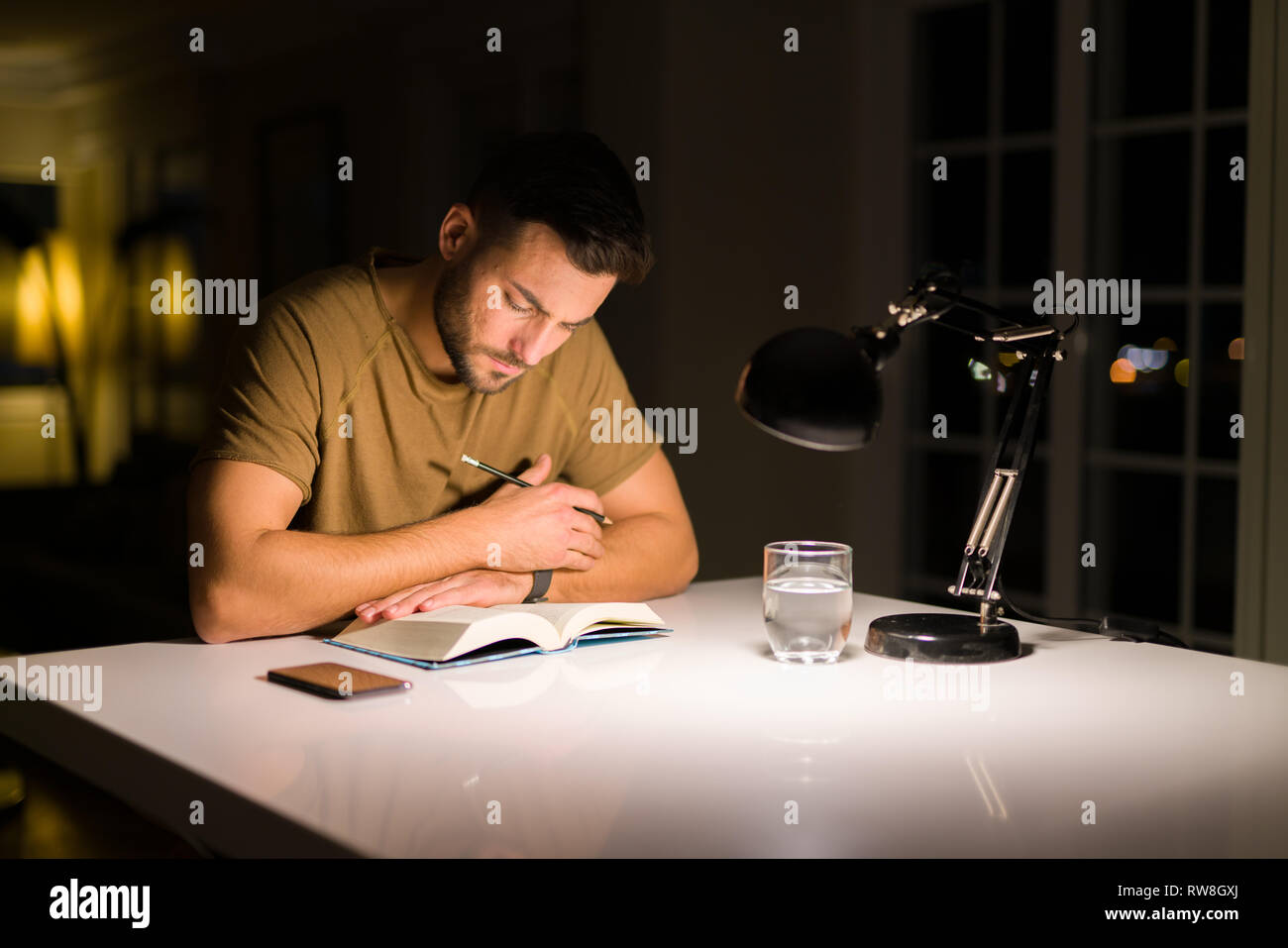 Young handsome man studying at home, reading a book at night Stock ...