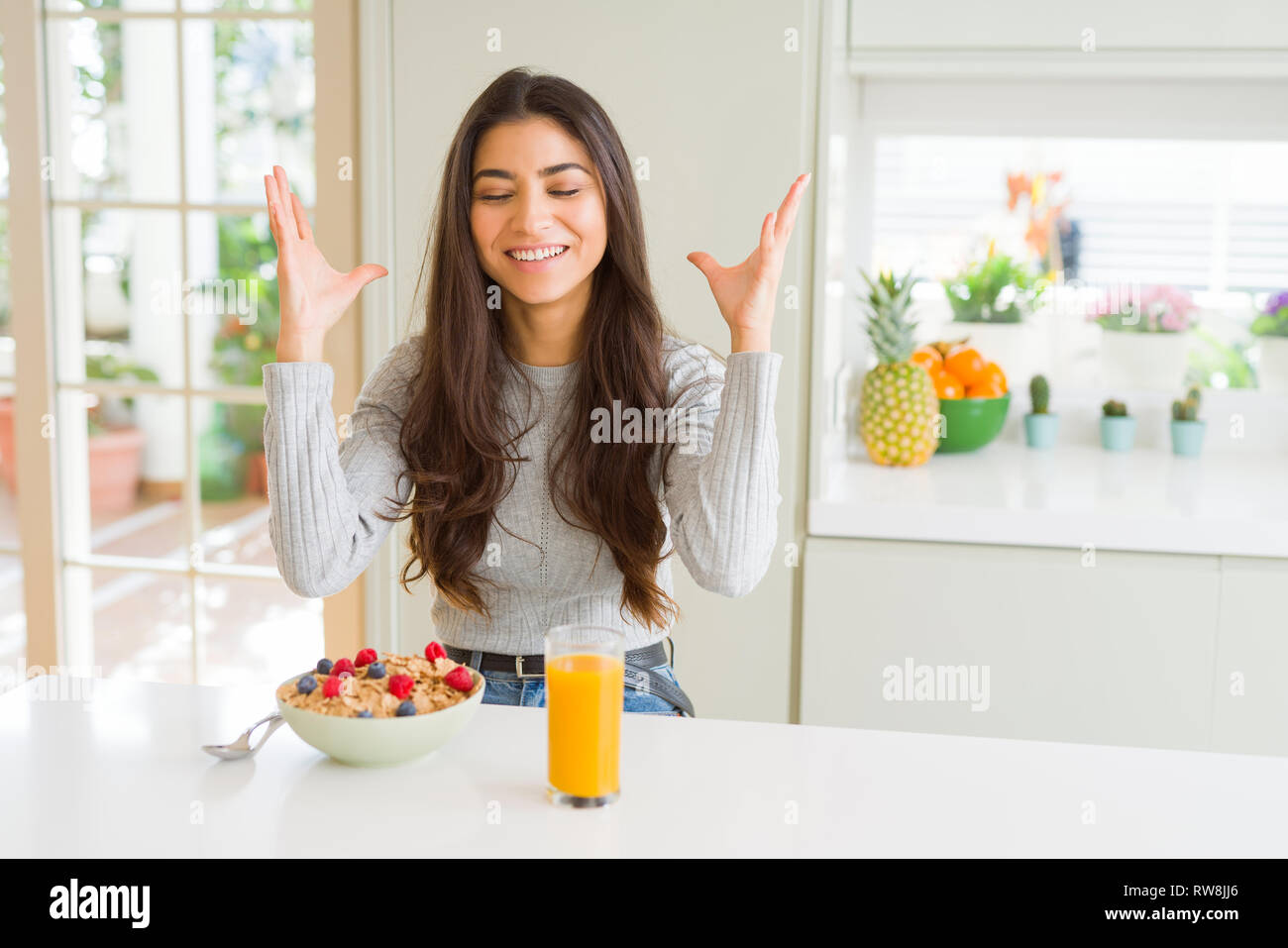 Young woman eating healthy breakfast in the morning celebrating mad and ...