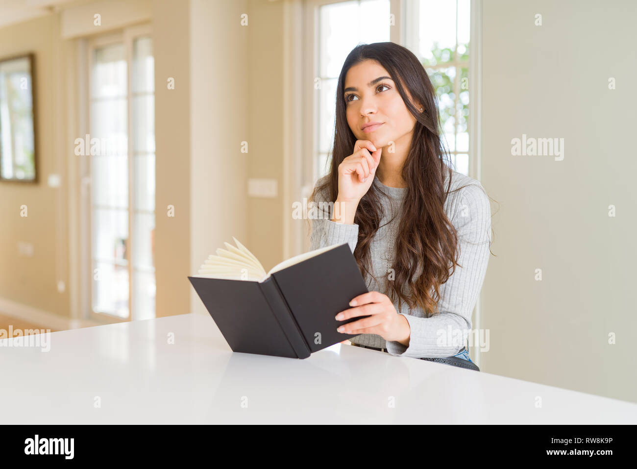 Young woman reading a book serious face thinking about question, very ...