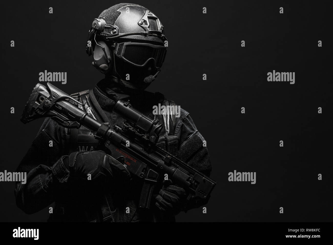 Spec ops police officer SWAT in black uniform and face mask, studio ...