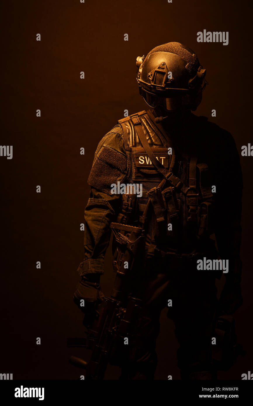 Spec ops police officer SWAT in black uniform and face mask, studio ...