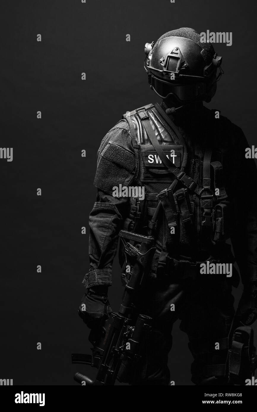 Spec ops police officer SWAT in black uniform and face mask, studio ...