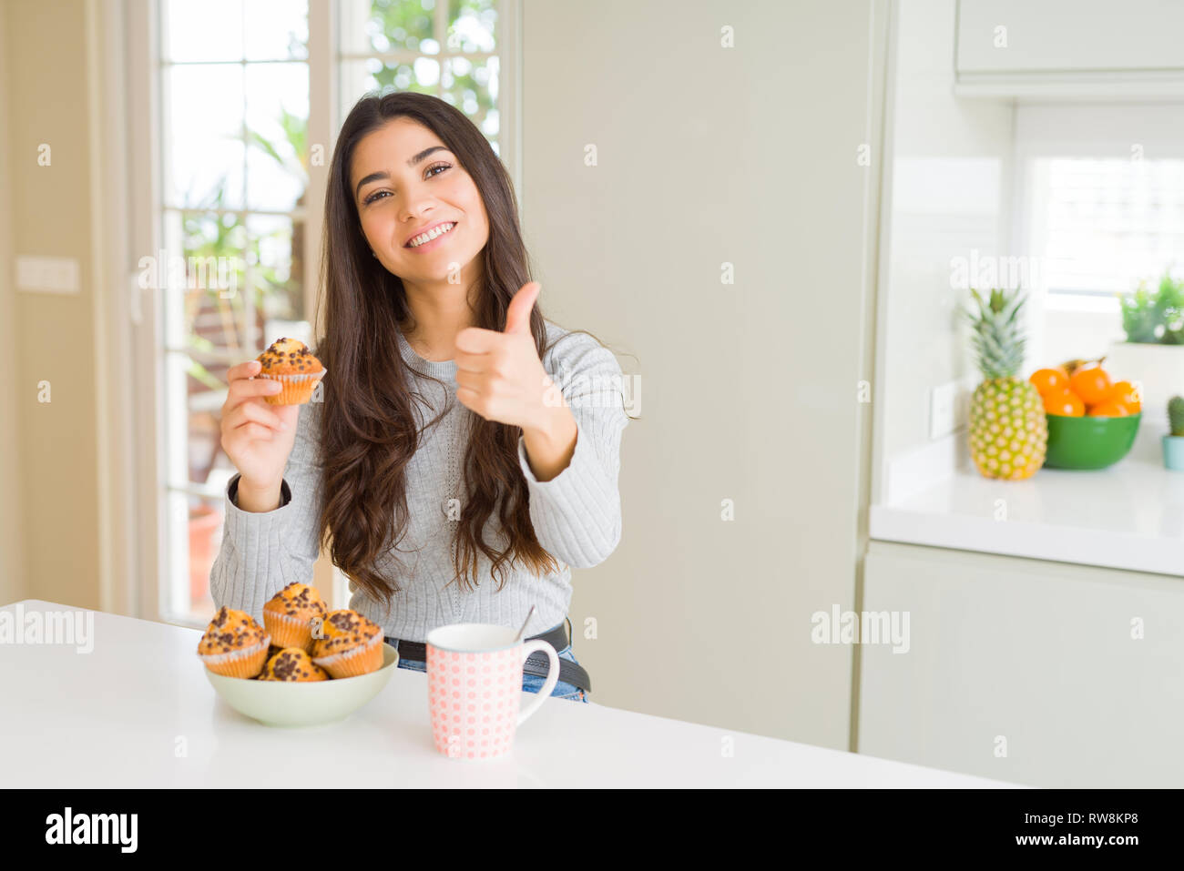 Young woman eating chocolate chips muffins and drinking coffee happy ...