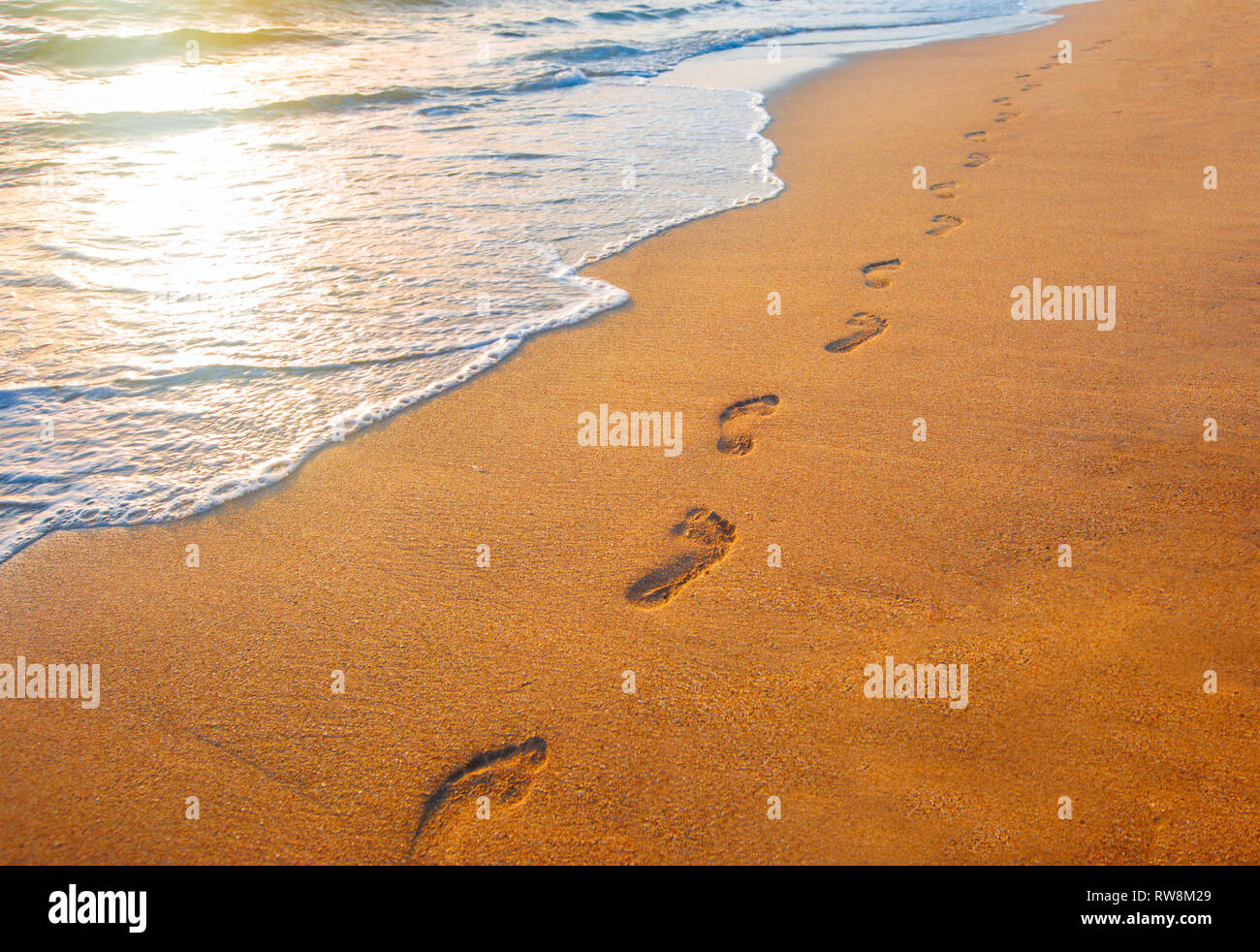 beach, wave and footprints at sunset time Stock Photo - Alamy