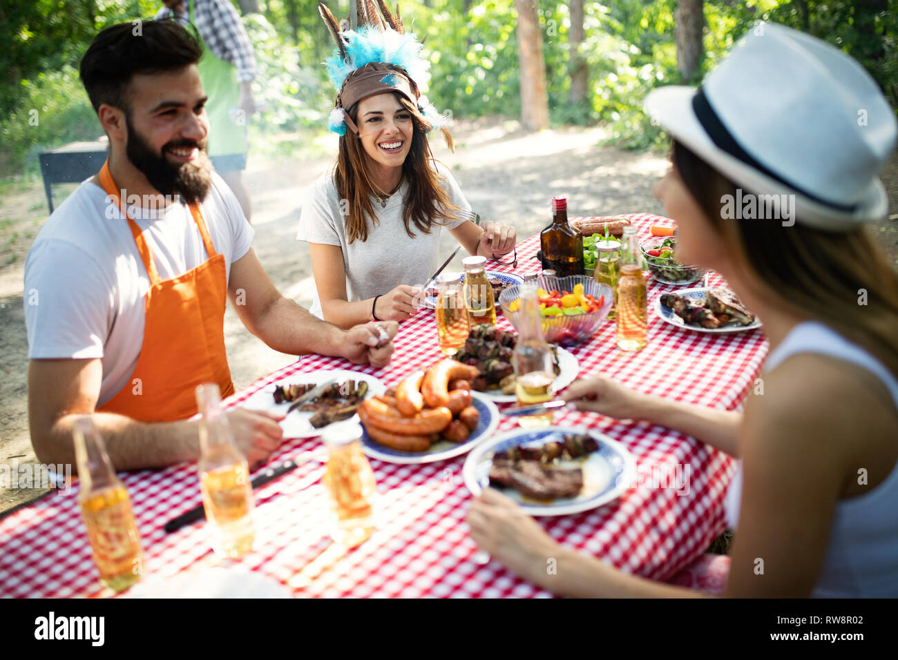 Group of happy friends eating and drinking beers at barbecue dinner ...