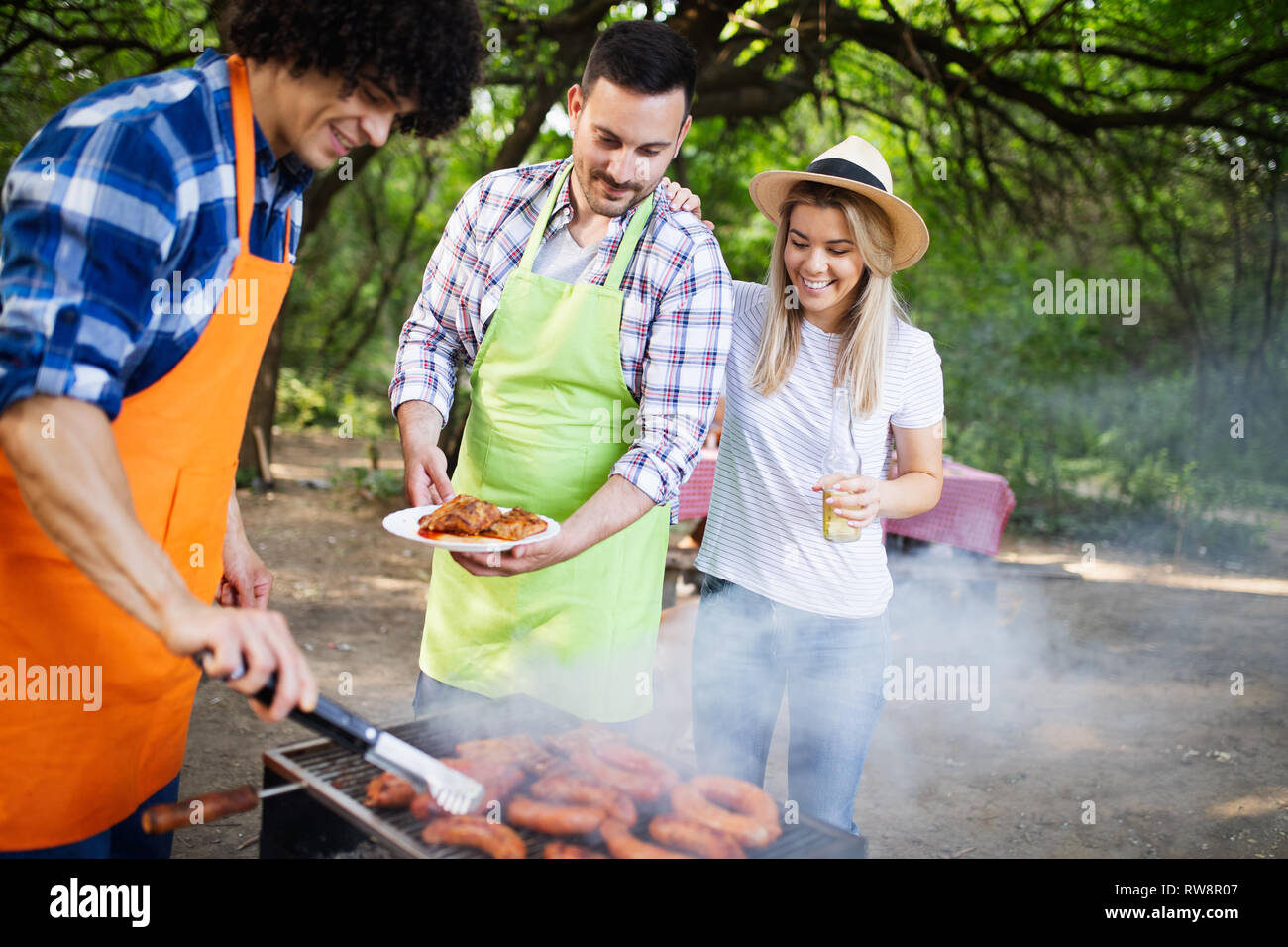 Friends having a barbecue party in nature while having fun Stock Photo ...