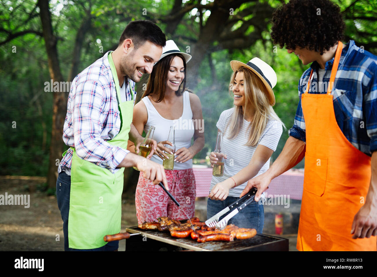 Group of happy friends eating and drinking beers at barbecue dinner ...