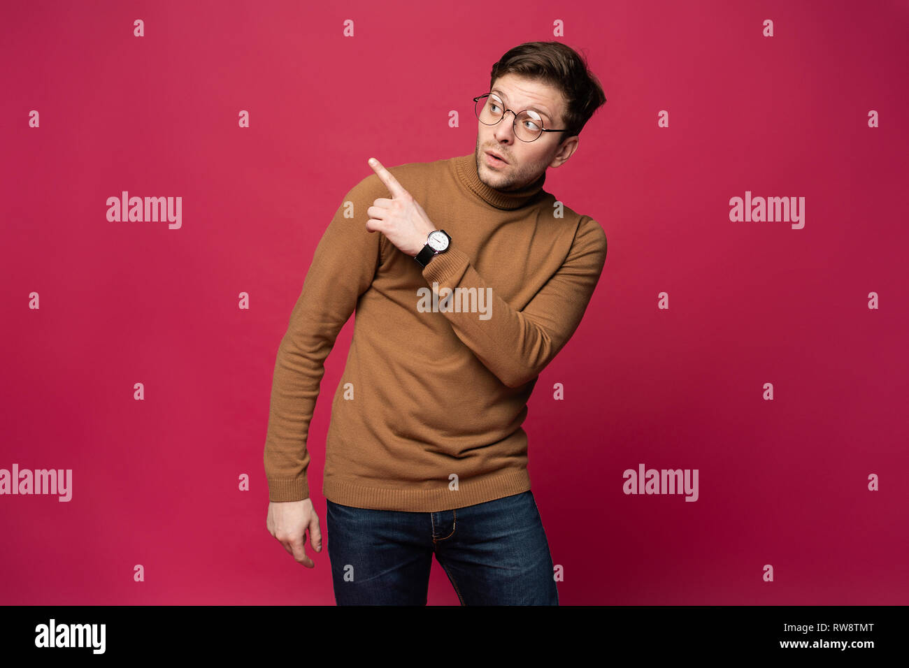 Portrait of a joyful young man pointing fingers away at copy space on ...