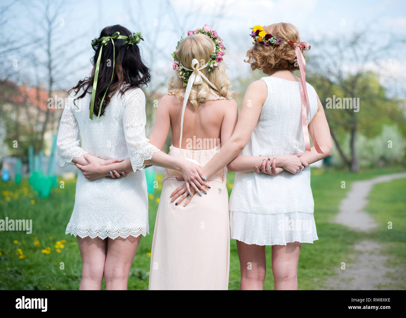 Back view of group of bridesmaids with bride in the middle. Holding ...
