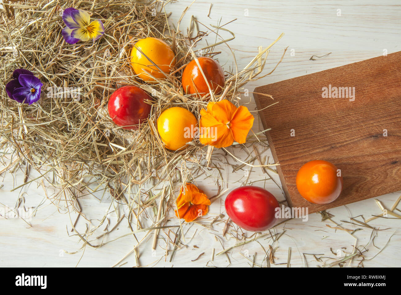 Stack of colorful easter eggs on straw with wooden table background ...