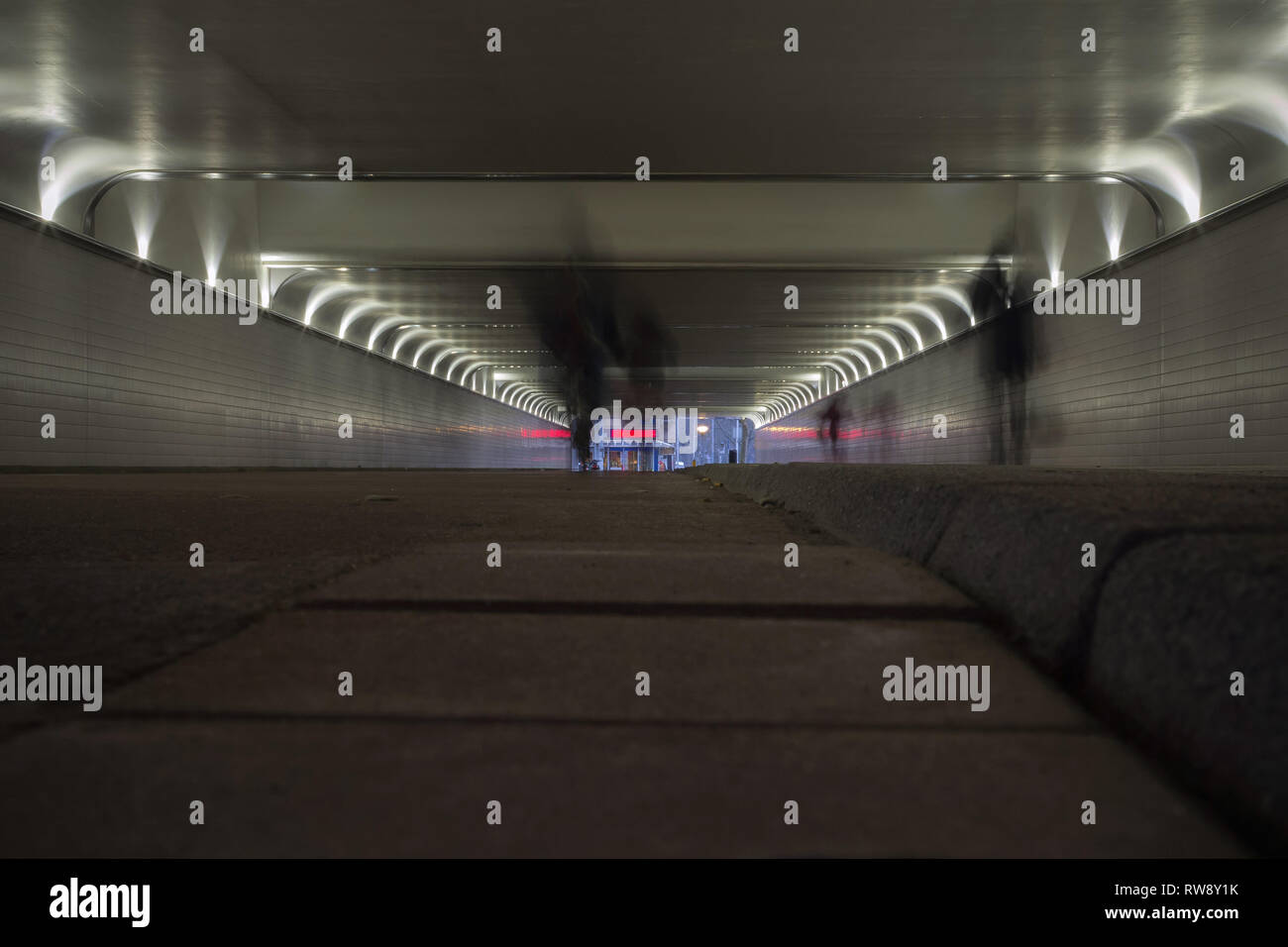 Perspective of an underground tunnel with silhouettes of people walking ...