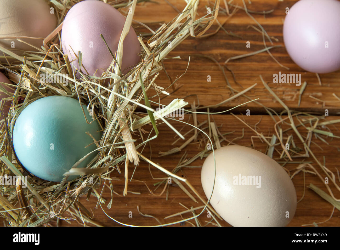 Stack of colorful easter eggs on straw with wooden table background ...