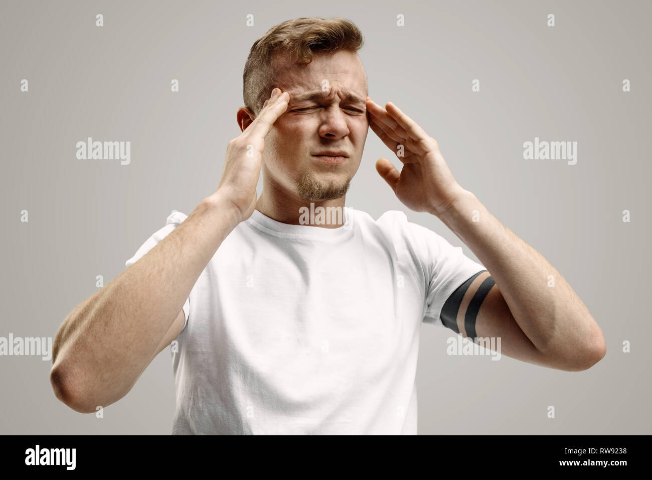 Man having headache. Business man standing with pain isolated on gray ...