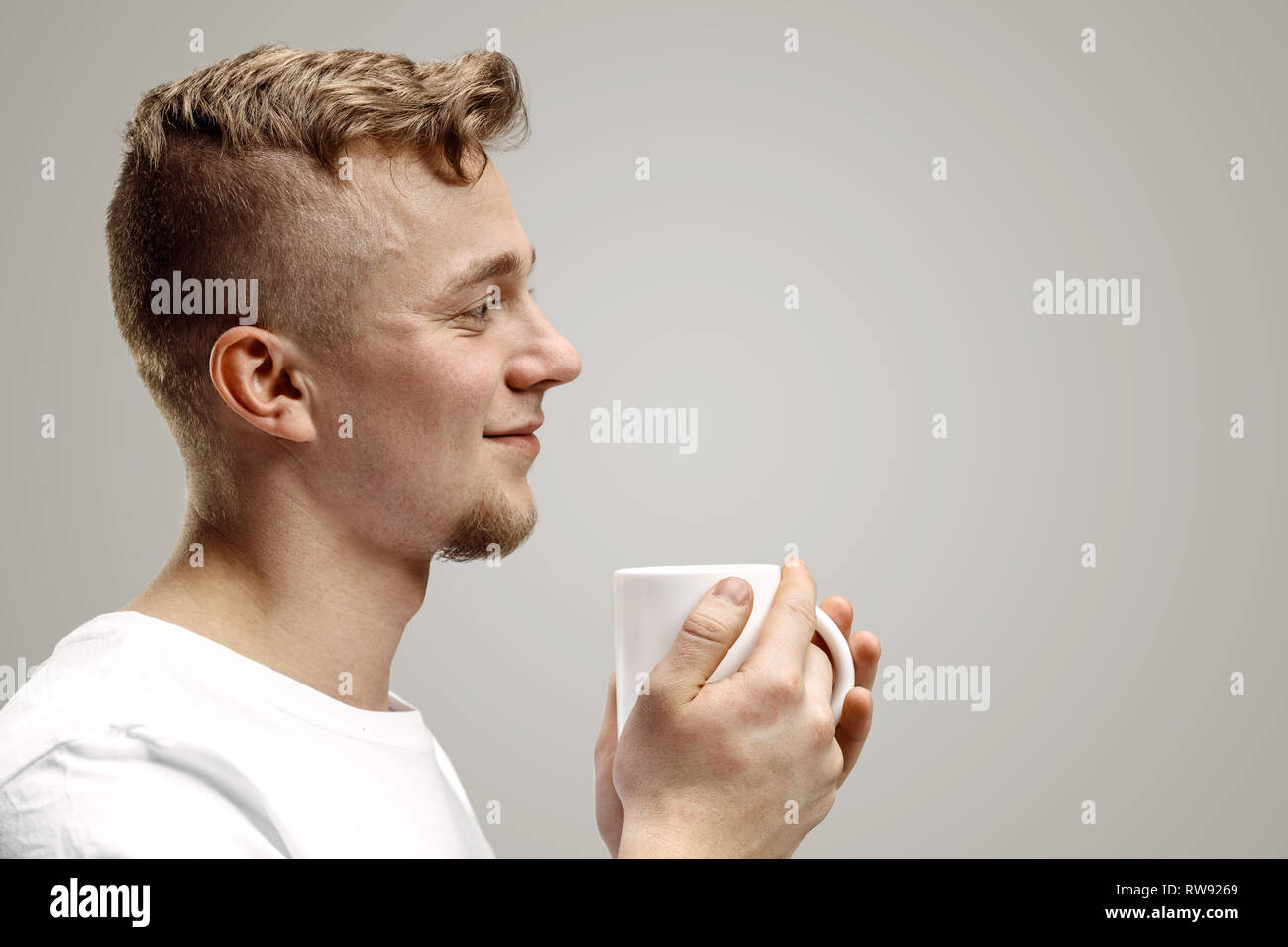 Taking a coffee break. Handsome young man holding coffee cup, smiling ...