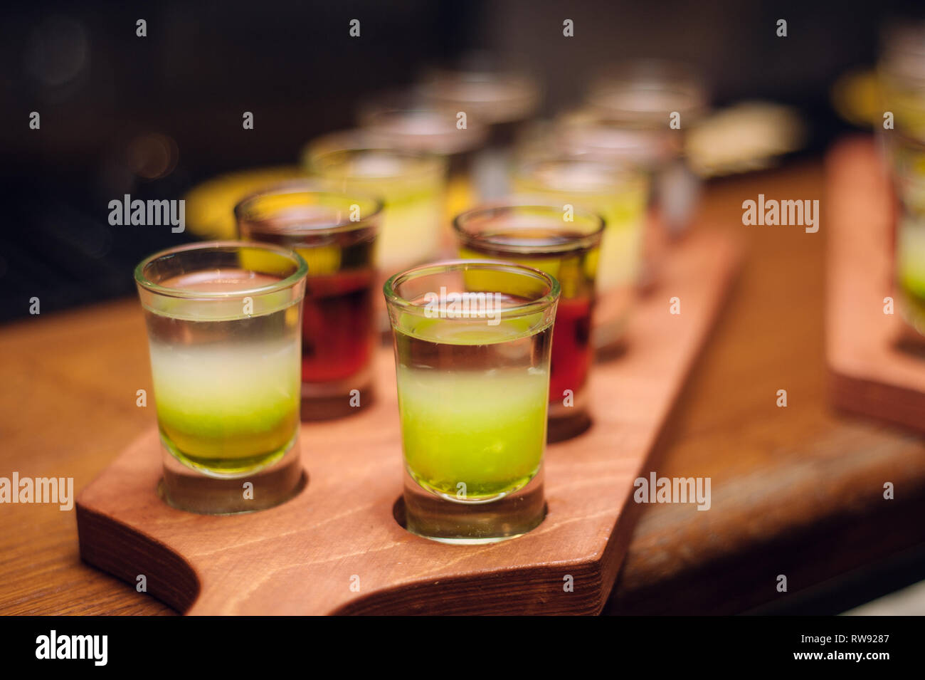 line of alcohol green shots at wooden desk at bar counter. row of ...