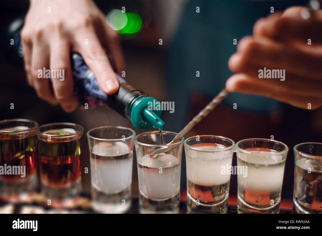 barman pouring shots at a bar counter. barman hands work close up. copy ...
