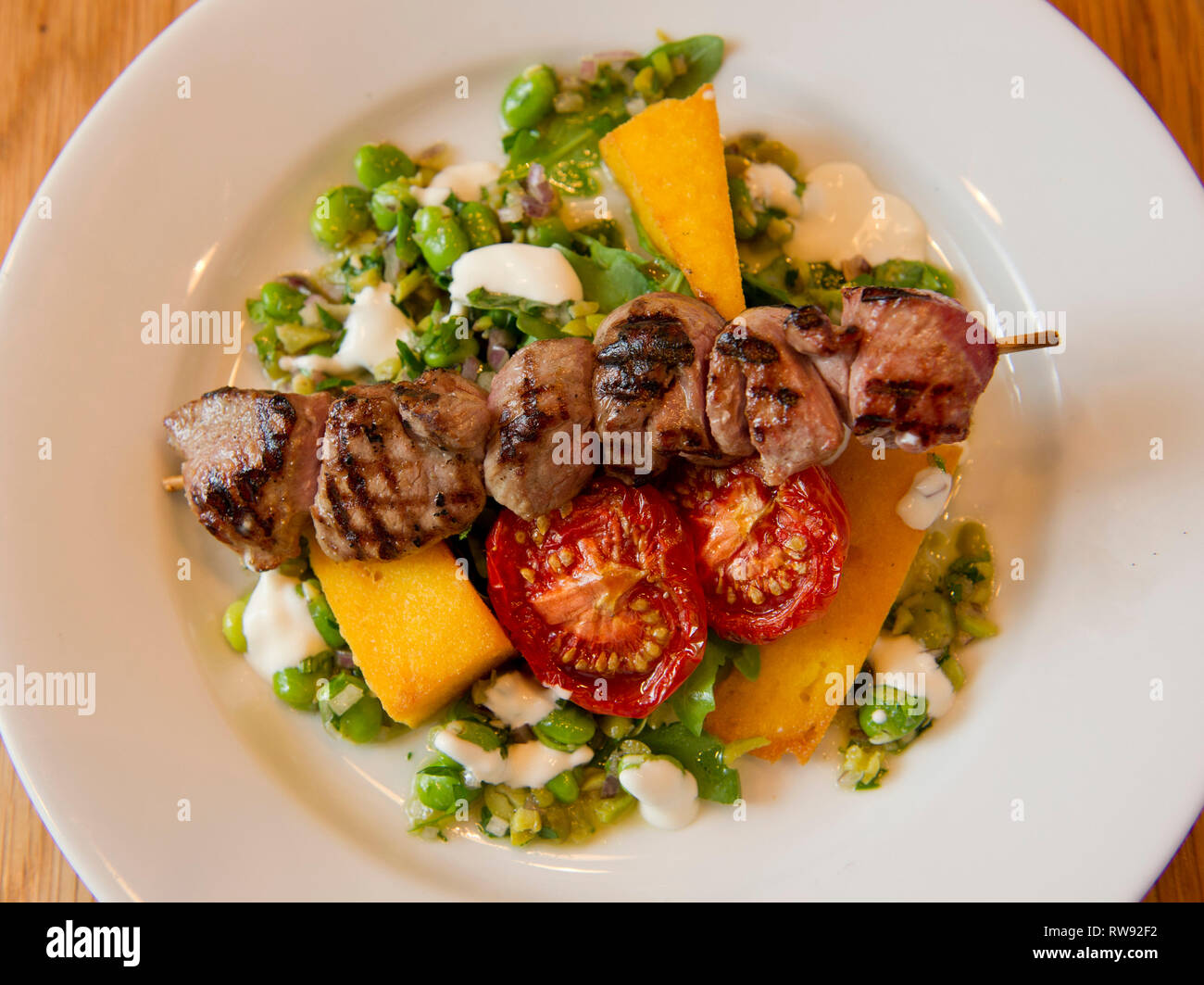 Pork kebab with potato, tomato and peas Stock Photo - Alamy