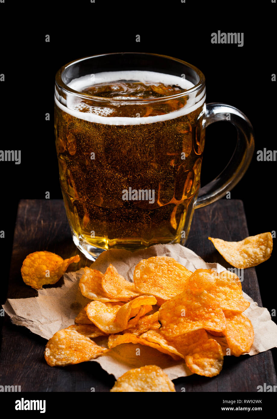 Glass of lager beer with potato crisps snack on vintage wooden board on ...