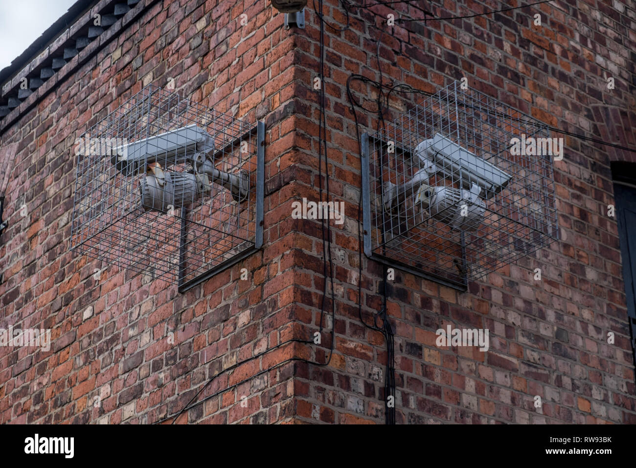 Two Security cameras on the THE END OF A BUILDING BOTH POINTING IN ...