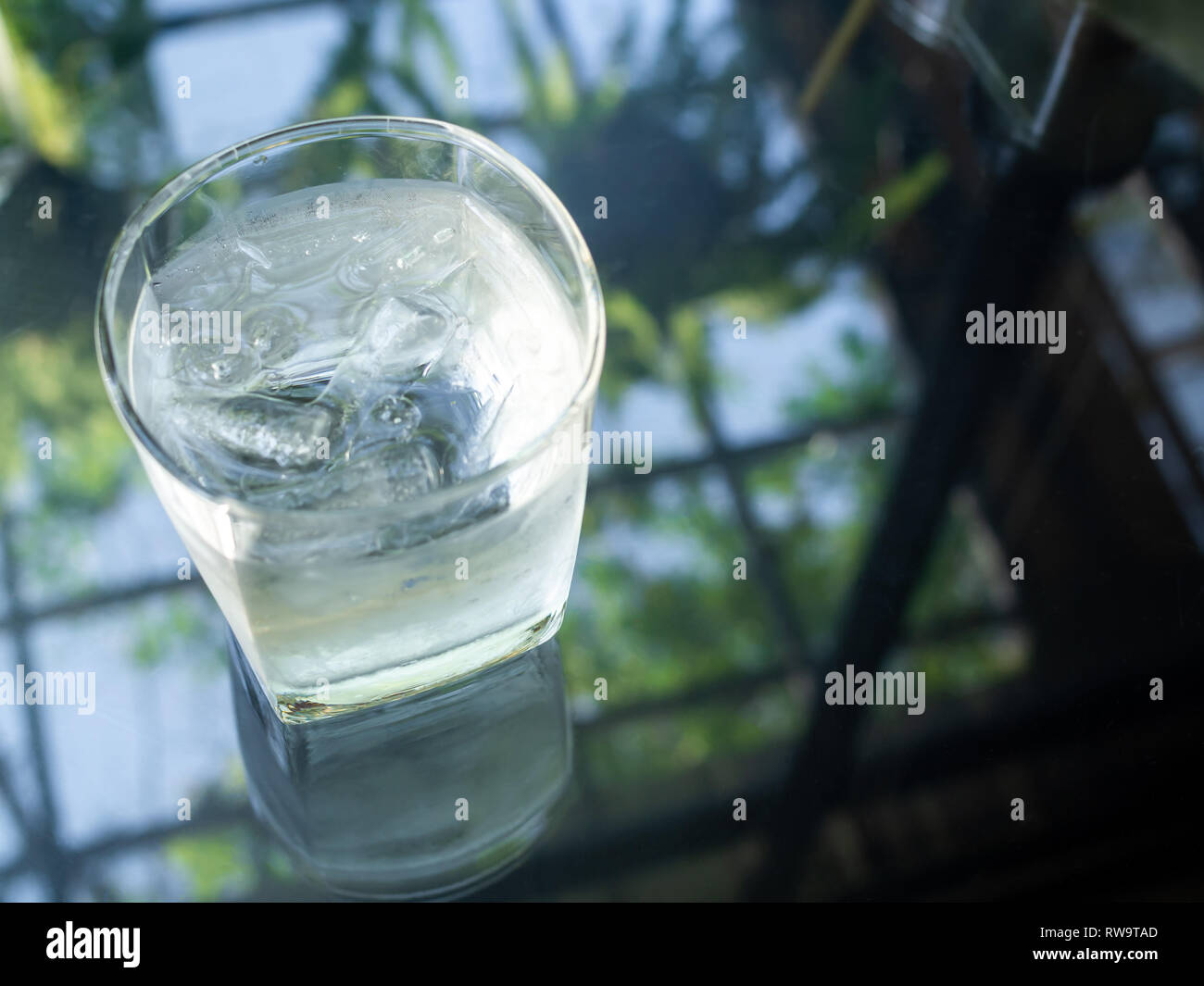 A glass of cold drinking water with ice on glass table with copy space ...
