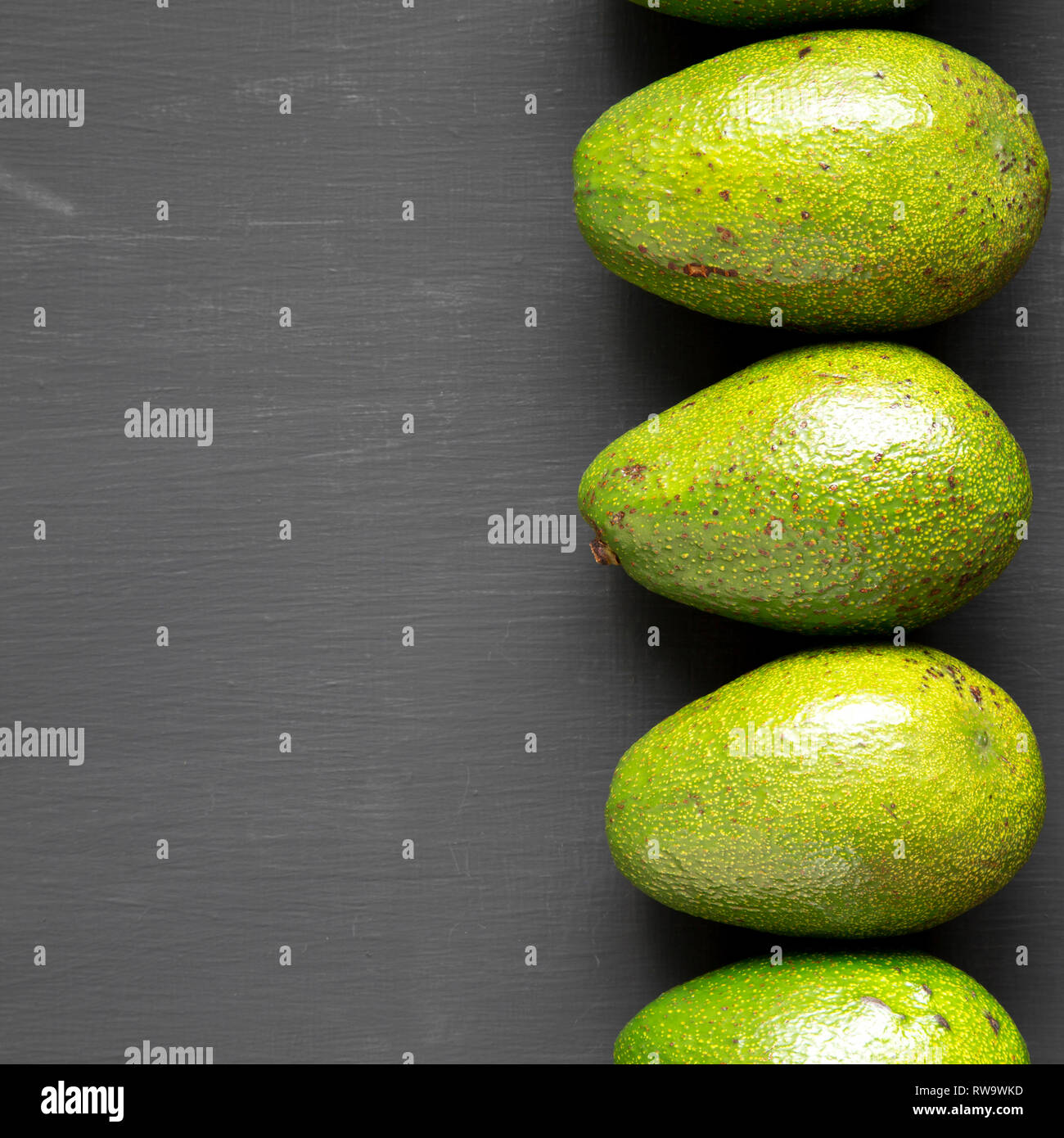 Whole avocados on dark black background, top view. Overhead, flat lay ...