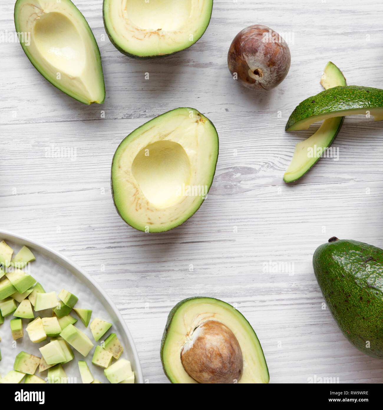 Whole and chopped avocados on white wooden surface, overhead view. Top ...