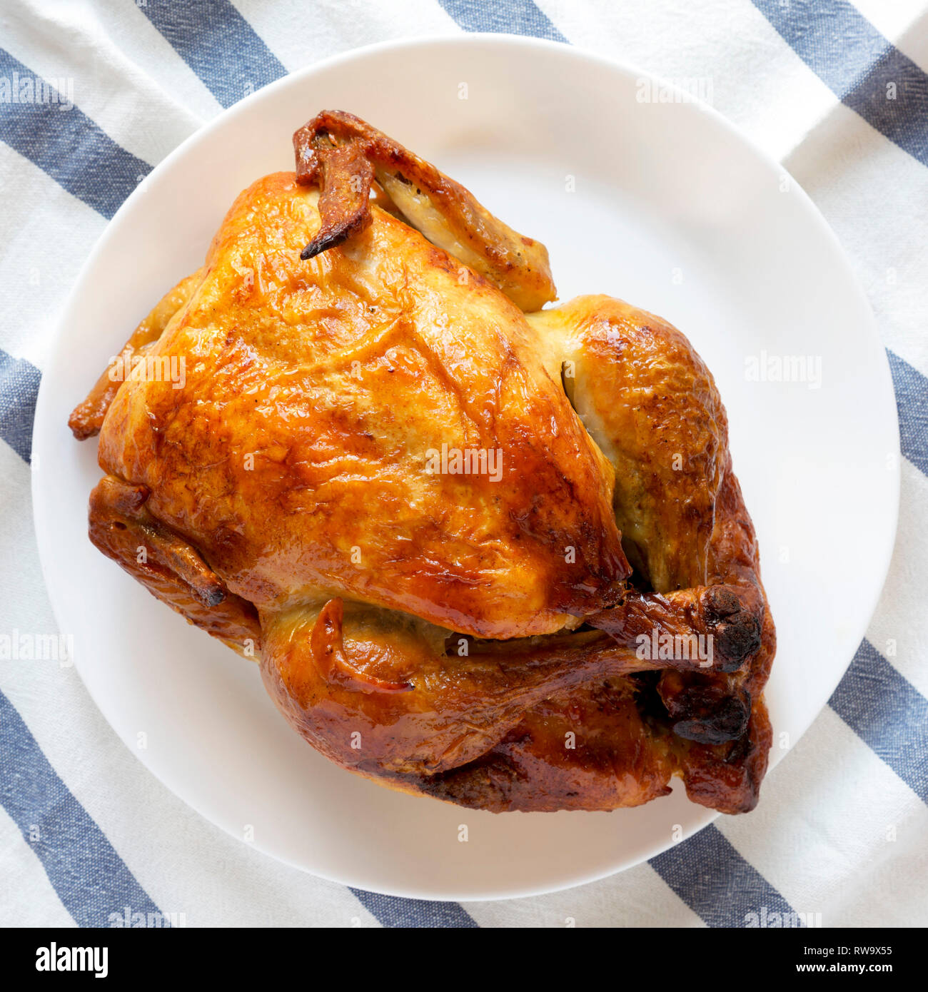 Homemade tasty rotisserie chicken on white plate, overhead view. Flat ...