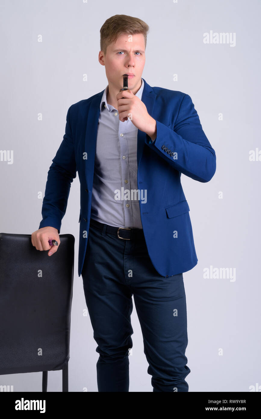 Young handsome blonde businessman smoking pipe while holding chair ...