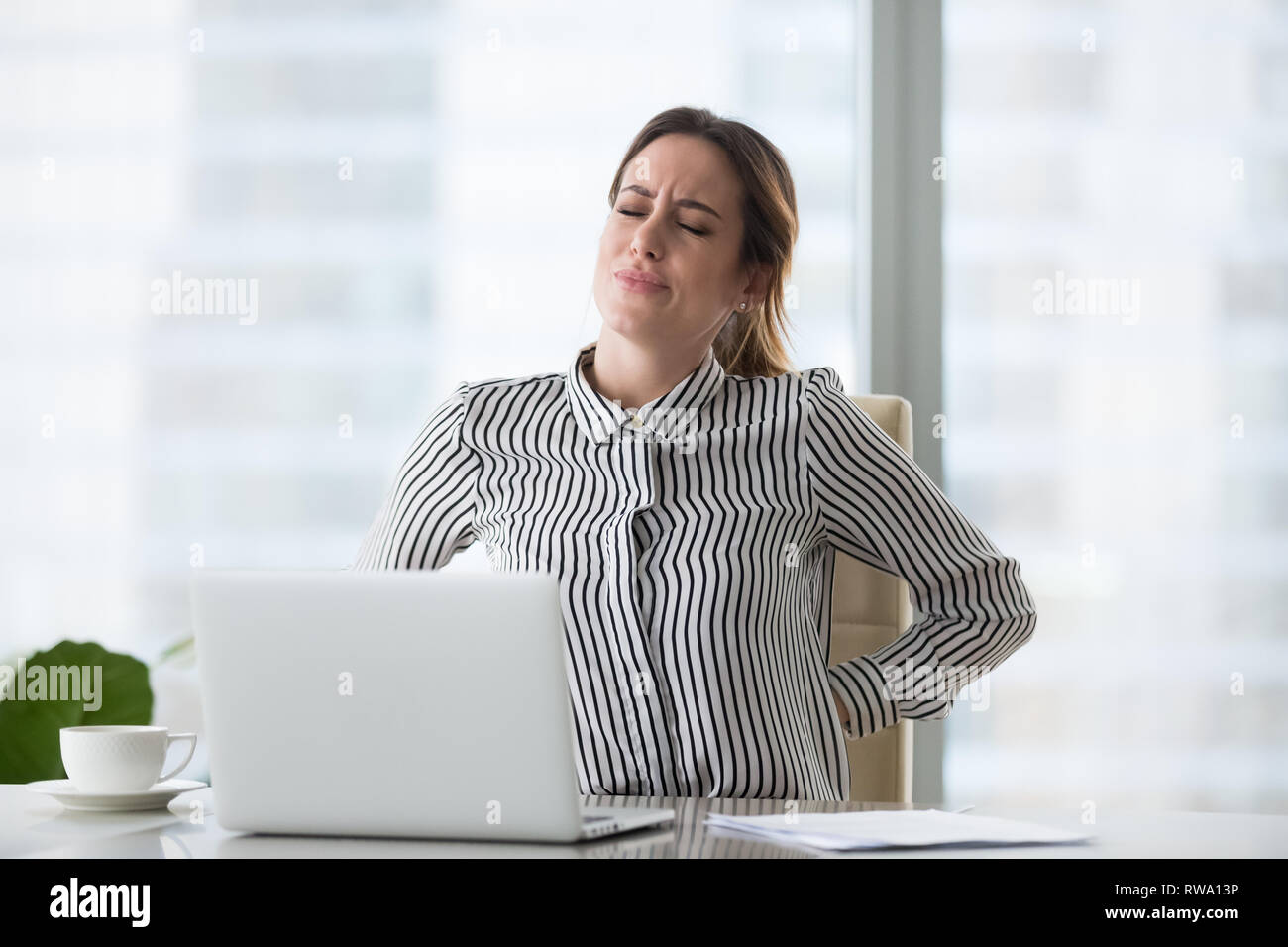 Tired fatigued businesswoman worker rubbing back feeling lower lumbar ...