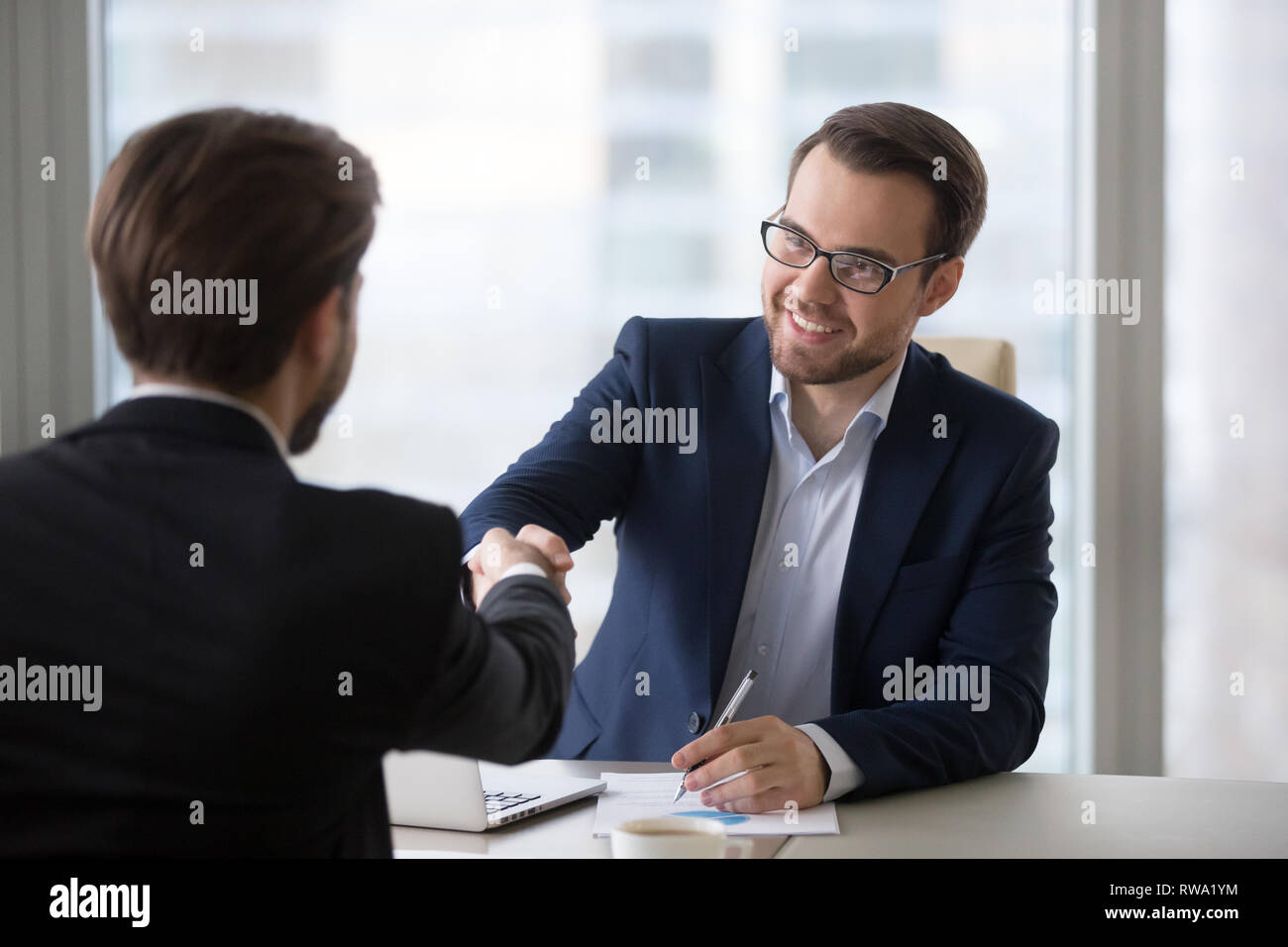 Smiling manager handshaking client applicant at meeting or job ...