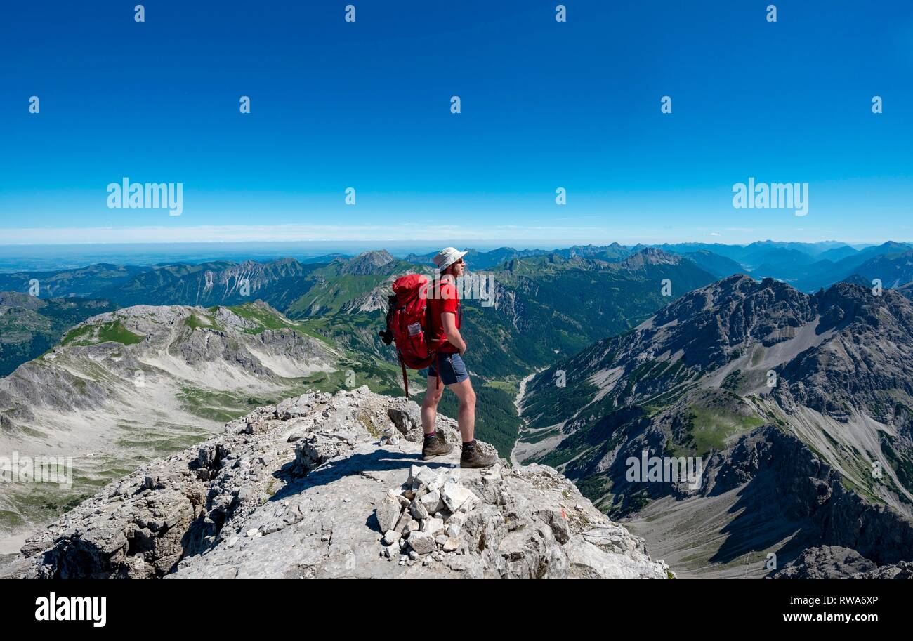 Hiker looks into the distance, summit of the Hochvogel, view into the ...