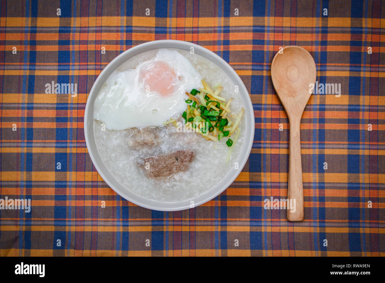 Rice porridge with soft boiled egg, ginger and chopped spring onion ...