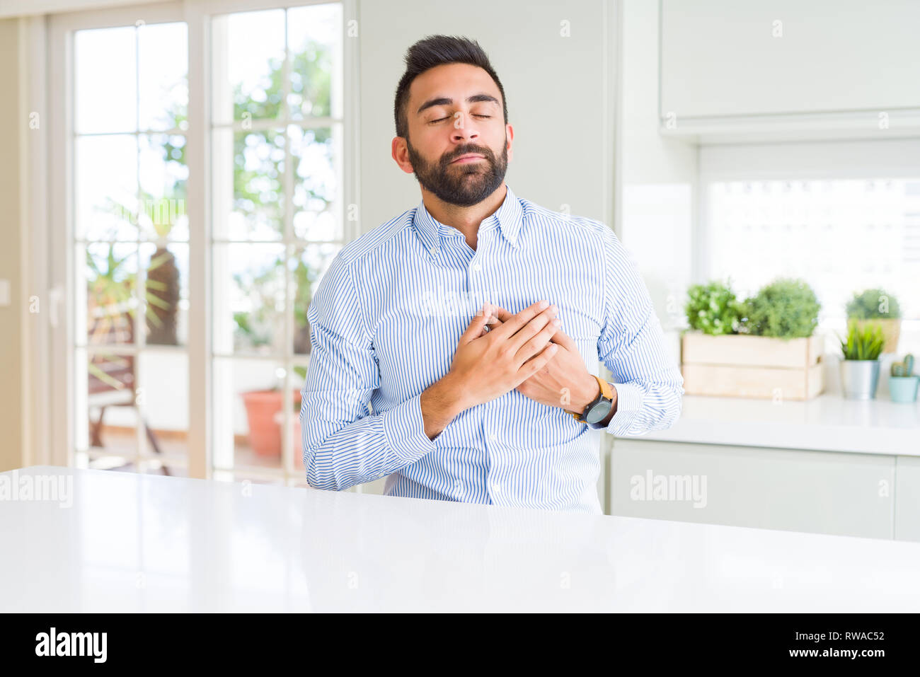 Handsome hispanic business man smiling with hands on chest with closed ...