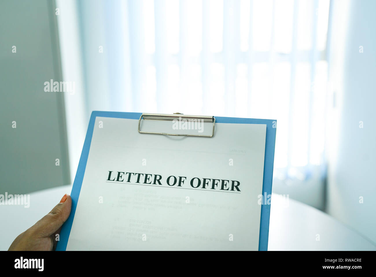 Hand holding letter of offer clipped on a board Stock Photo - Alamy