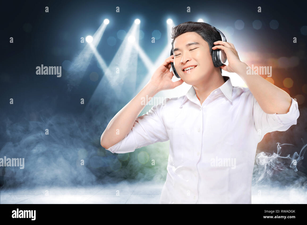 Handsome asian man in white shirt with headphones enjoy the music over ...