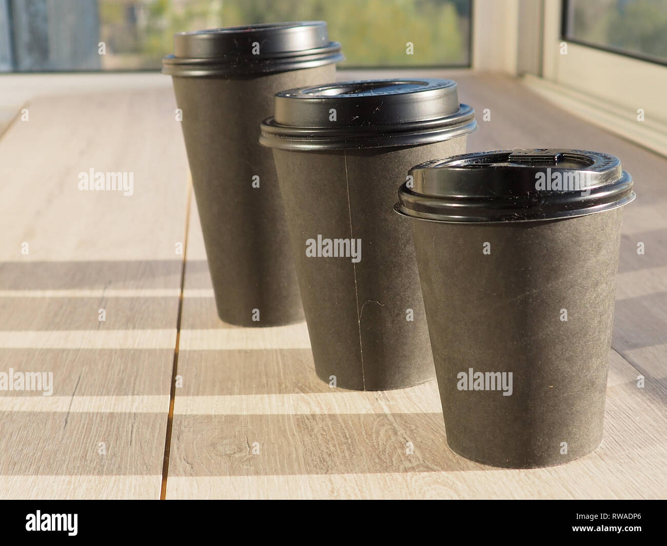 Cups of coffee different sizes on cafe table near window Stock Photo ...