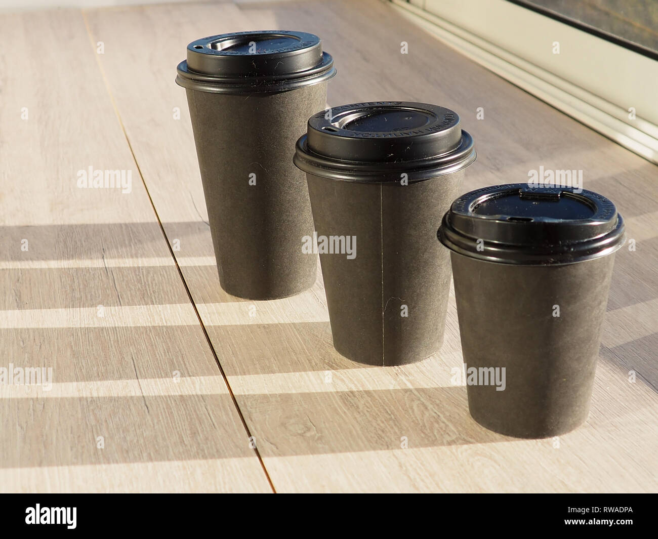 Cups of coffee different sizes on cafe table near window Stock Photo ...