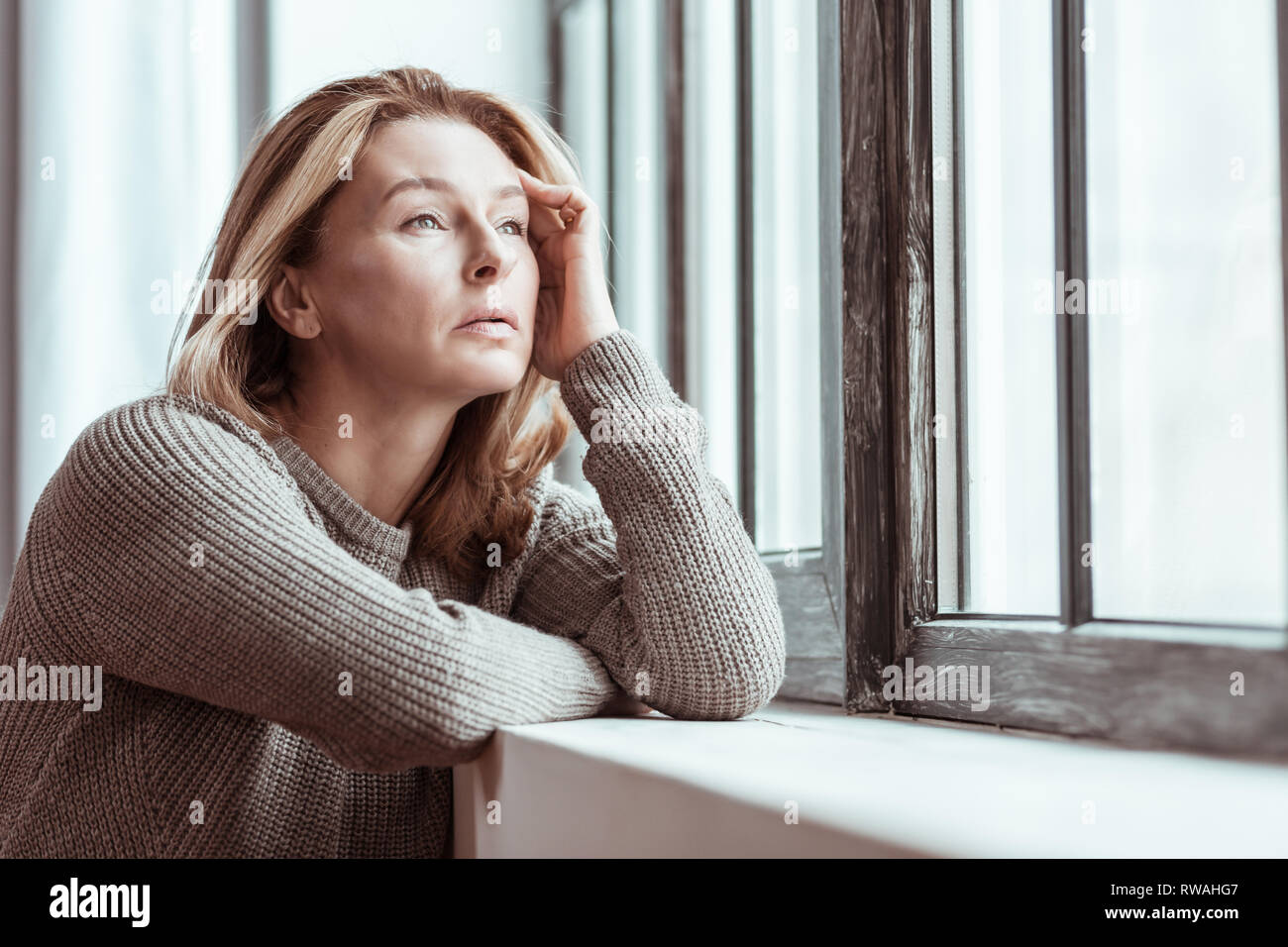 Beautiful mature woman feeling stressed looking into window Stock Photo ...
